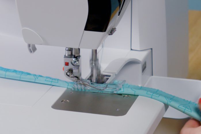 Serger piping; side view of blue-fabric wrapped cording being fed ...